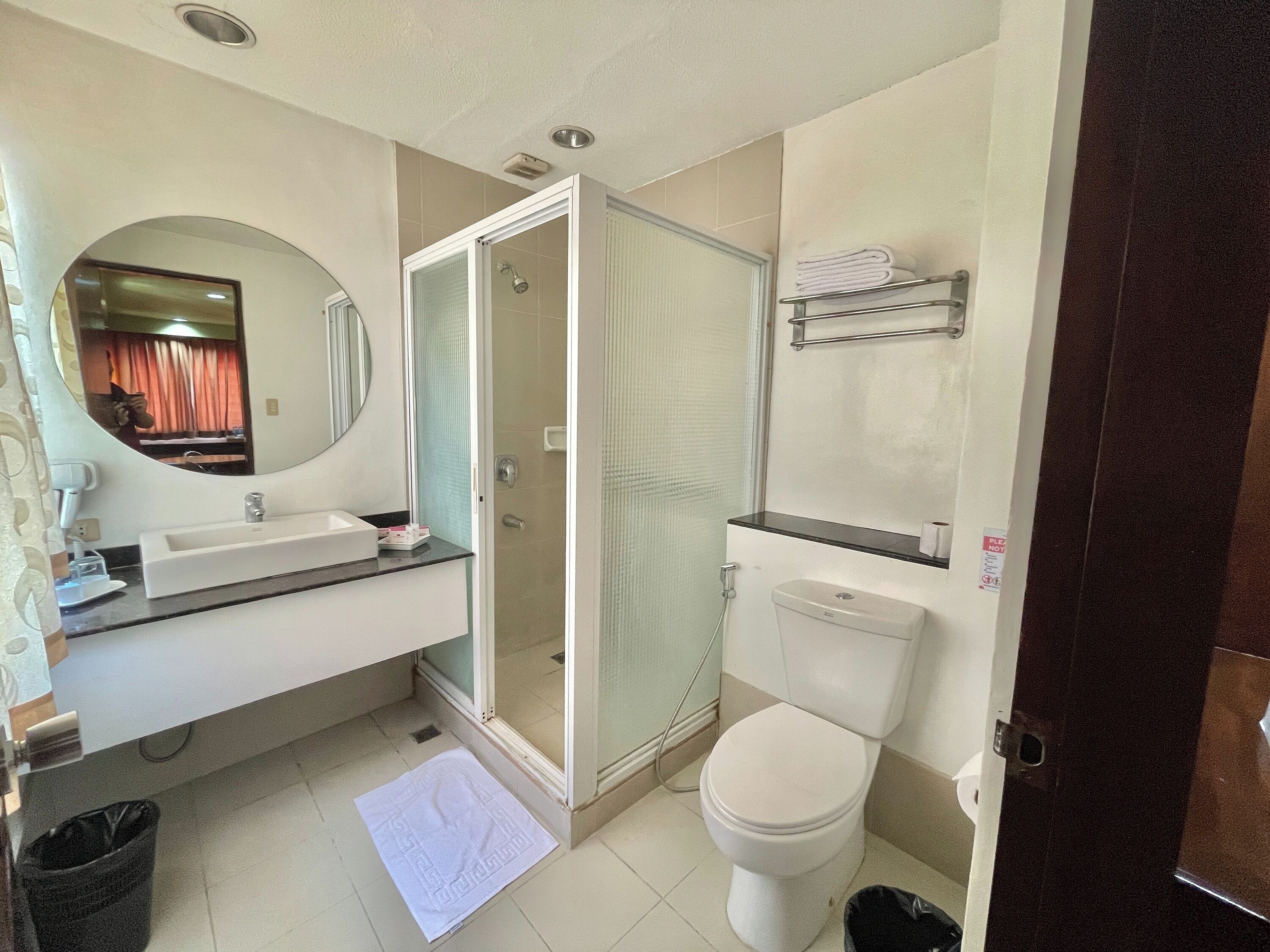 Uma casa de banho moderna com chuveiro em cabine de vidro, sanita e lavatório com espelho em cima.