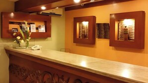 Uma receção com bancada de mármore, painéis de madeira e obras de arte emolduradas na parede.