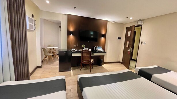 Quarto de hotel com duas camas, uma escrivaninha com cadeira, televisão e minibar.