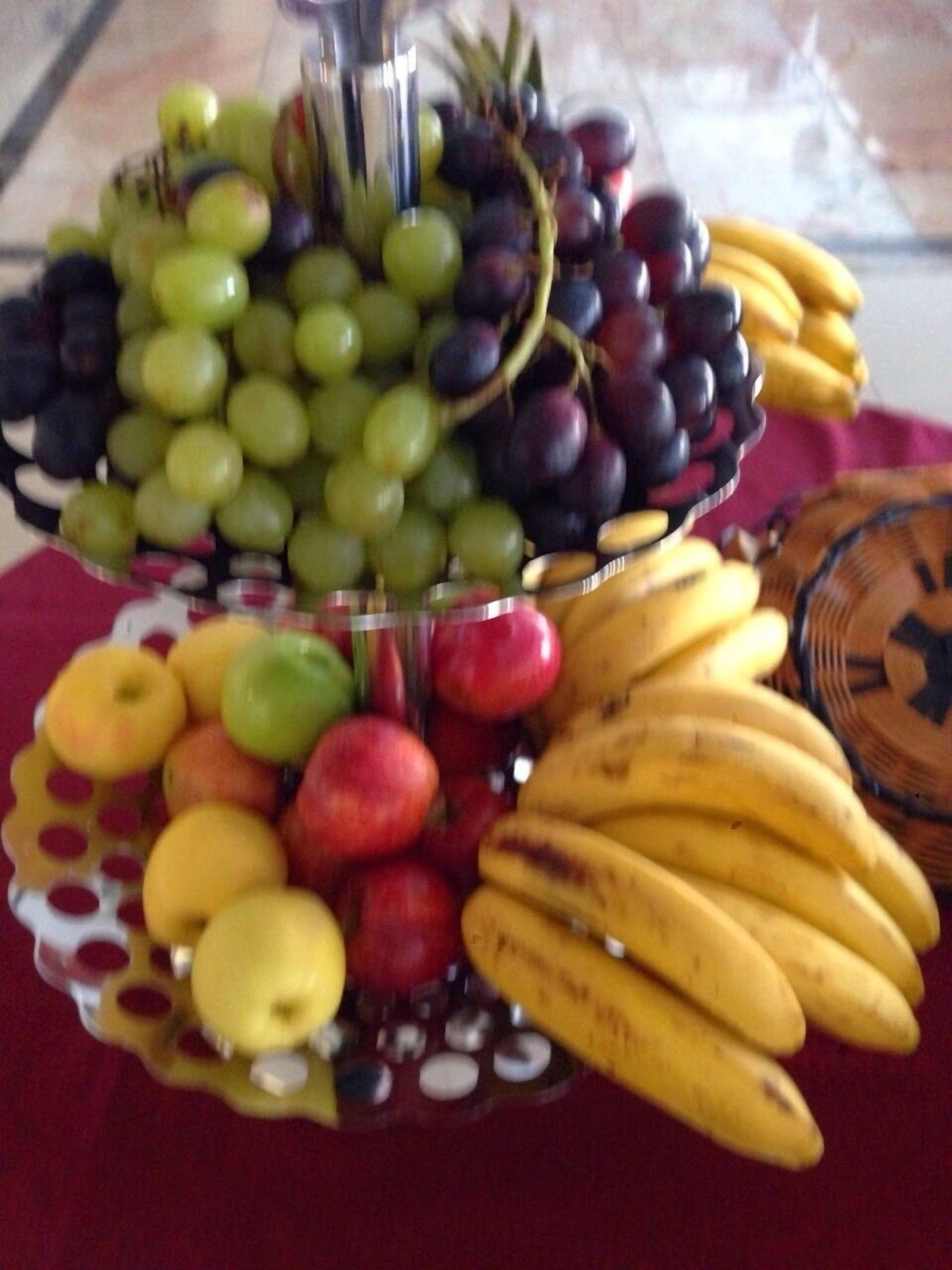 Uma tábua de frutas com uvas, ameixas, maçãs e bananas.