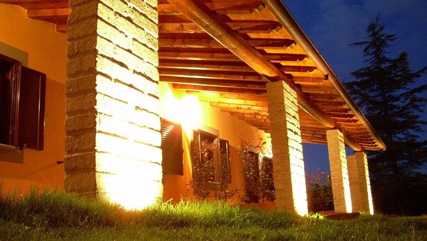 Um edifício com fachada de tijolos, vigas de madeira e varanda coberta com iluminação.