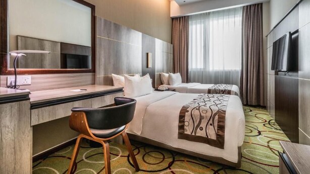 Quarto de hotel com uma cama grande, uma escrivaninha com cadeira, televisão e um espelho amplo.