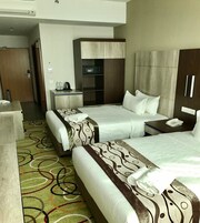 Quarto de hotel com duas camas, uma escrivaninha, frigobar e banheiro.