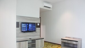 Quarto de hotel com televisão integrada, um pequeno espaço de estar e um tapete estampado.