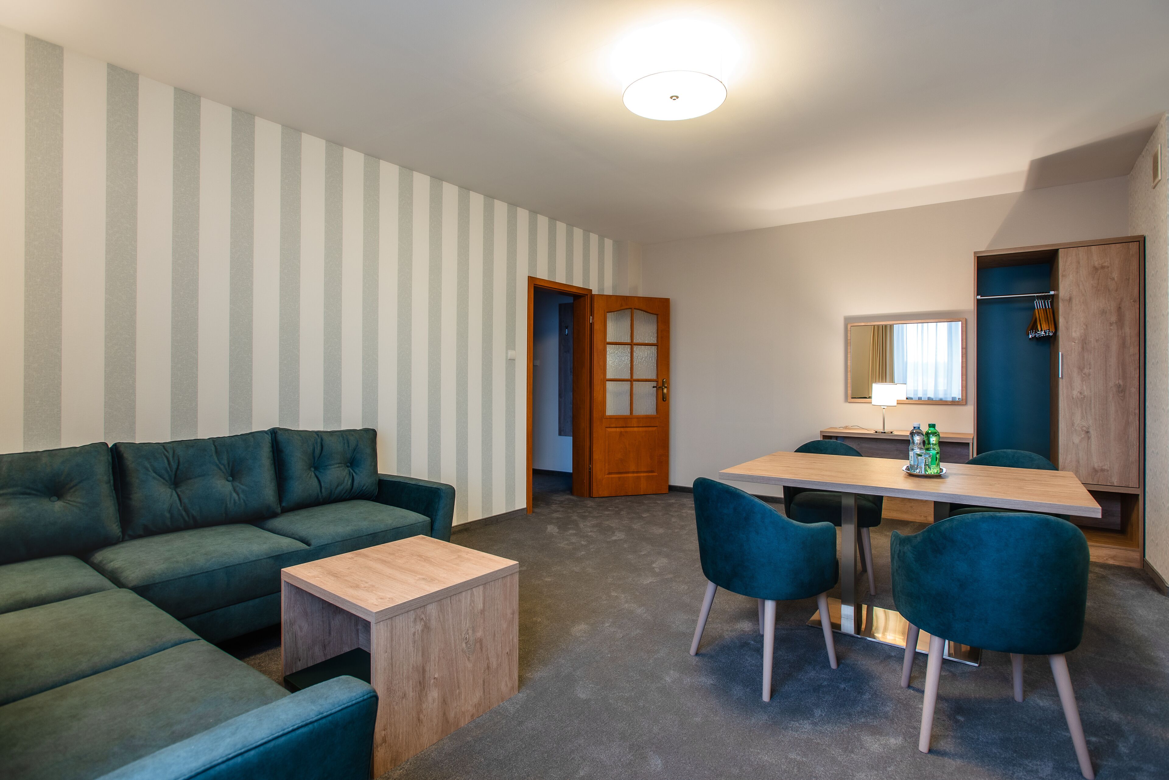Uma sala de estar moderna com um sofá seccional, uma pequena mesa de madeira e um espaço de jantar com mesa e cadeiras.