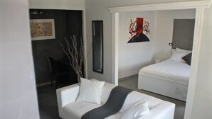Quarto de hotel moderno com sofá branco, cama e escrivaninha.