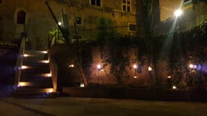 Vista noturna de um edifício com escadaria, iluminado por postes de luz.