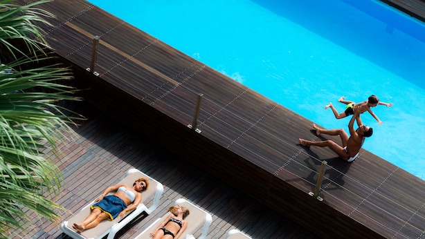 Uma área na beira da piscina com espreguiçadeiras e um deck de madeira.
