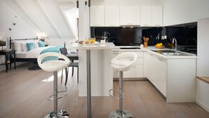 Uma cozinha moderna com armários brancos, uma ilha central e banquetas.