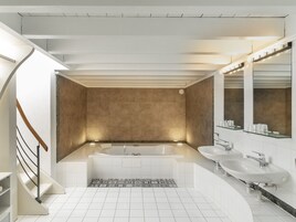 Casa de banho moderna com uma banheira grande, duas pias e um espelho.