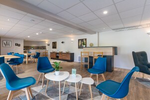 Um interior moderno com cadeiras azuis, mesas brancas e um balcão de recepção.