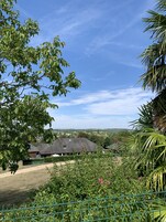 Paisagem rural com uma casa rodeada de vegetação e céu limpo.