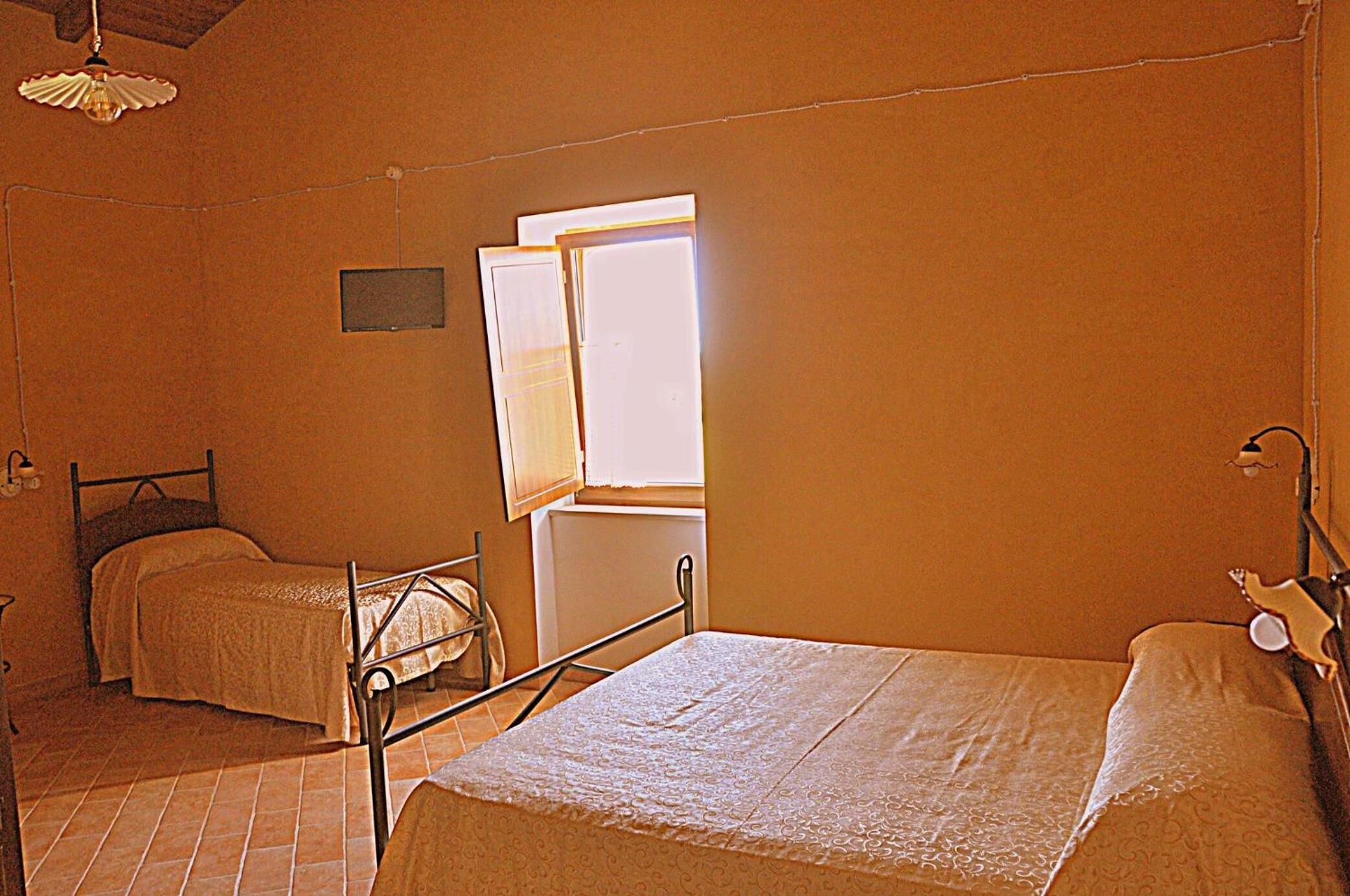 Quarto pequeno e individual com uma cama, uma cadeira, um radiador e uma janela.