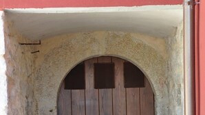 Um arco de pedra que dá acesso a uma porta de madeira.