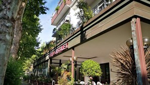 Um hotel chamado "HOTEL RISTALEX", com fachada moderna, plantas externas e céu claro.