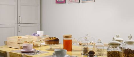 Uma mesa de café da manhã com diversos alimentos, uma cafeteira e um jarro de leite.