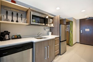 Cozinha moderna com micro-ondas embutido, geladeira de aço inoxidável e lava-louças.