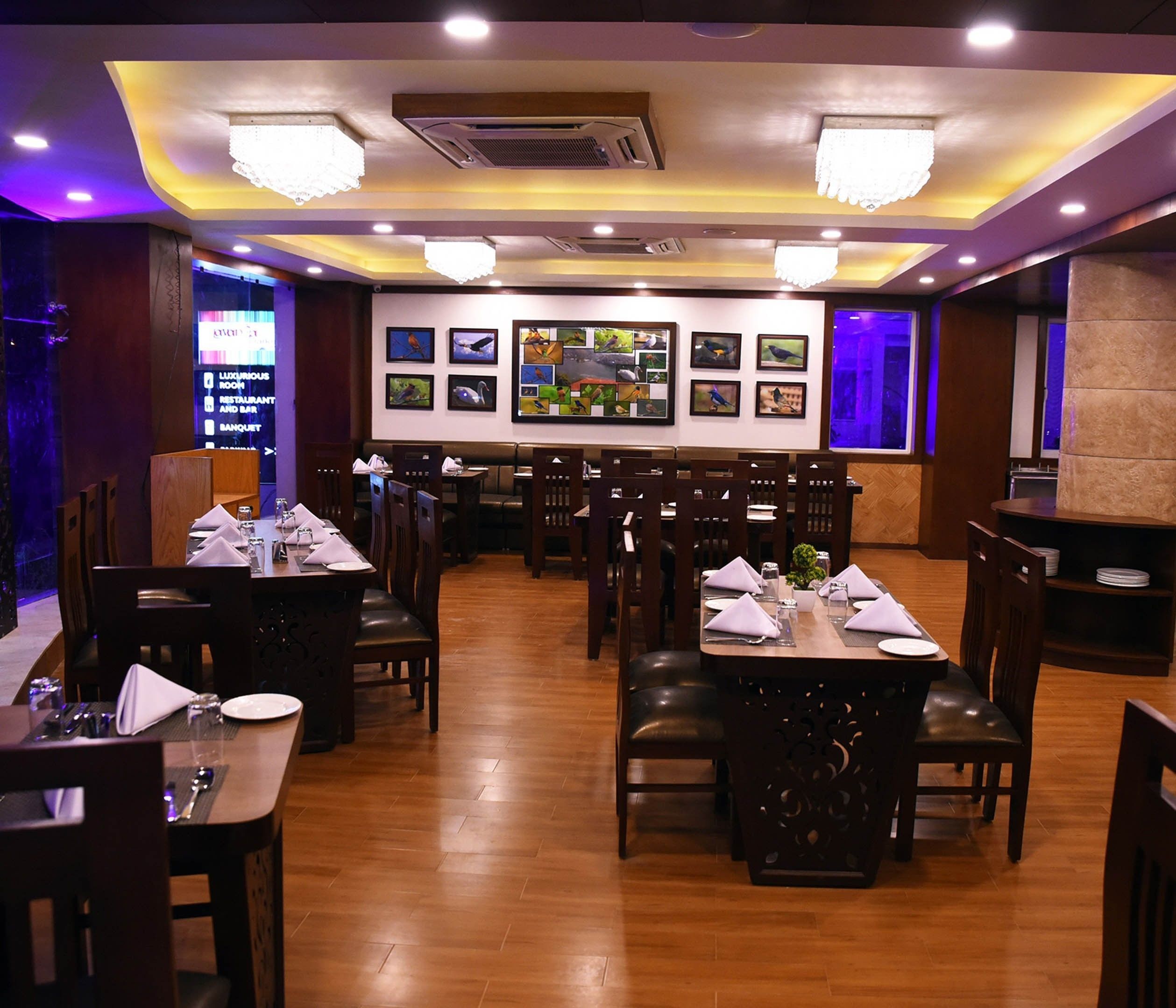 Um restaurante com chão de madeira, várias mesas de jantar com cadeiras e luminárias no teto.
