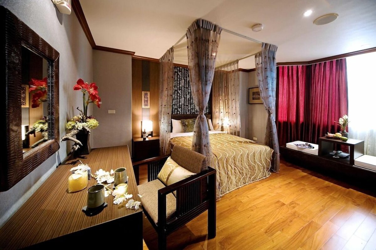 Quarto com cama de dossel, mesa de cabeceira com velas e um espelho.