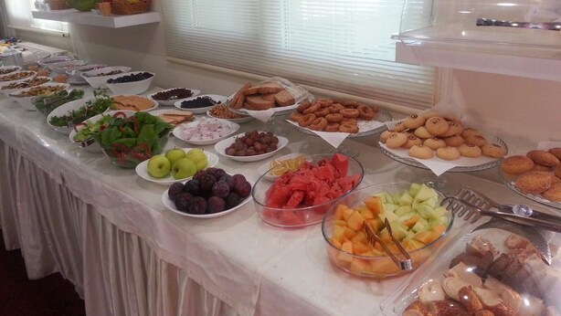 Uma mesa de buffet com diversos alimentos, incluindo frutas, legumes e doces.