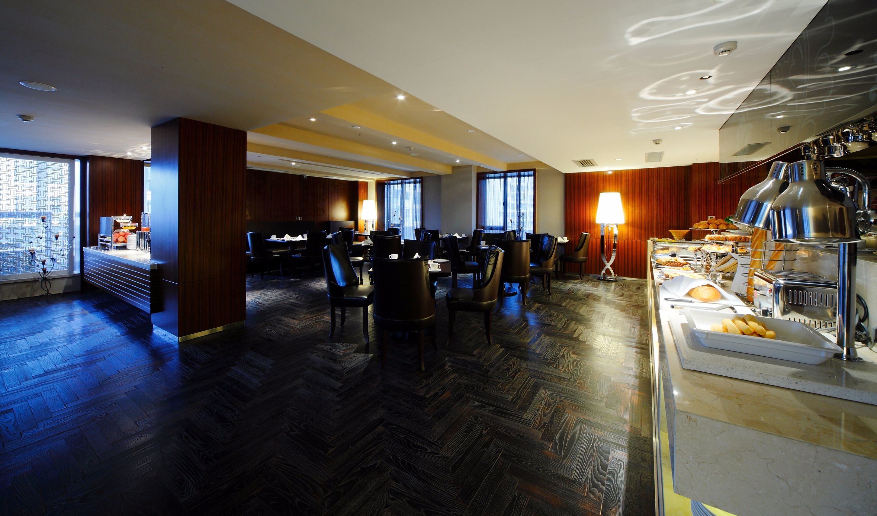 Uma sala de jantar de hotel com buffet, várias mesas e cadeiras.