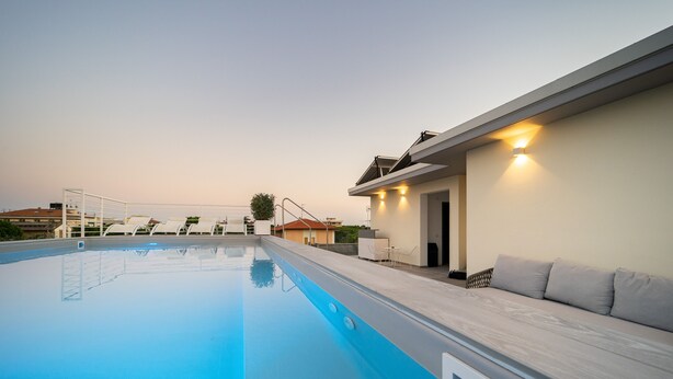 Piscina no terraço com vista clara dos edifícios ao redor e área de estar moderna ao ar livre.