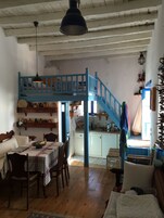 Um interior rústico com escada de madeira, área de jantar com mesa e cadeiras, e cozinha.