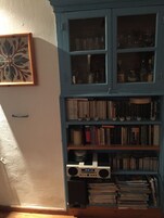 Quarto com um armário azul contendo livros, CDs e um rádio.