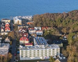 Uma cidade costeira com mistura de edifícios residenciais e comerciais, incluindo um hotel notável com telhado plano e vários andares.
