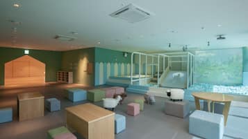 Espaço de recreação infantil com assentos coloridos e um escorrega.