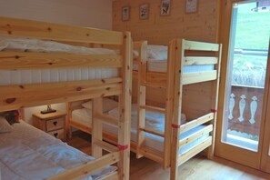 Quarto com beliche de madeira, uma mesinha de cabeceira e janela com vista para o exterior.
