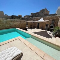 Piscina com muro de pedra e cobertura branca.