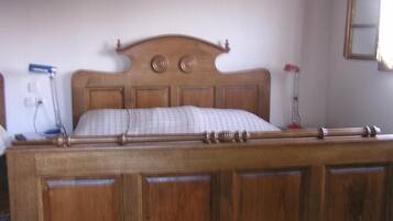Uma cama de madeira com cabeceira, um abajur e um espelho na parede.