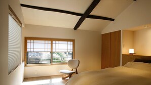 Quarto com cama grande, janela com persianas, cadeira e guarda-roupa de madeira.