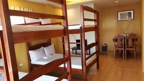 Quarto com beliches de madeira, uma escrivaninha e uma cadeira.
