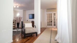 Uma sala de estar moderna com um sofá, uma televisão na parede e piso de madeira.
