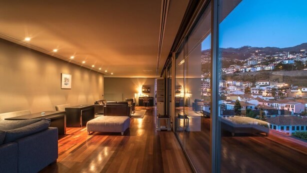 Uma sala de estar moderna com uma grande janela com vista para a cidade.