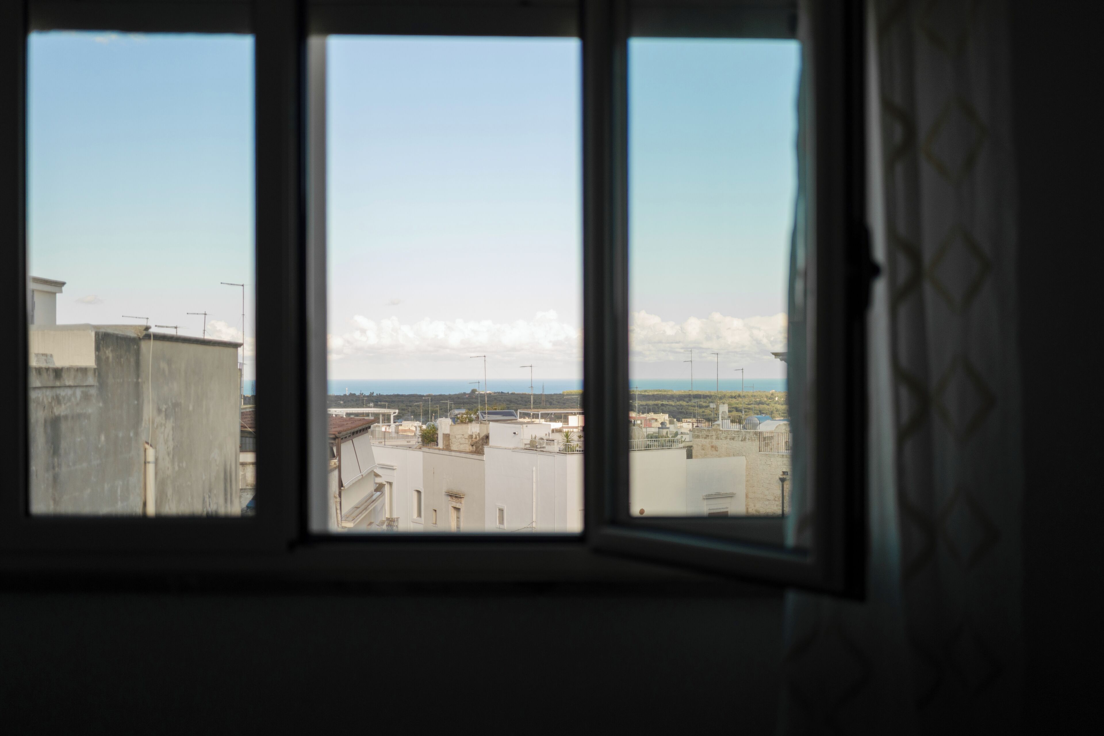 Vista pela janela de um horizonte urbano com edifícios e céu claro.
