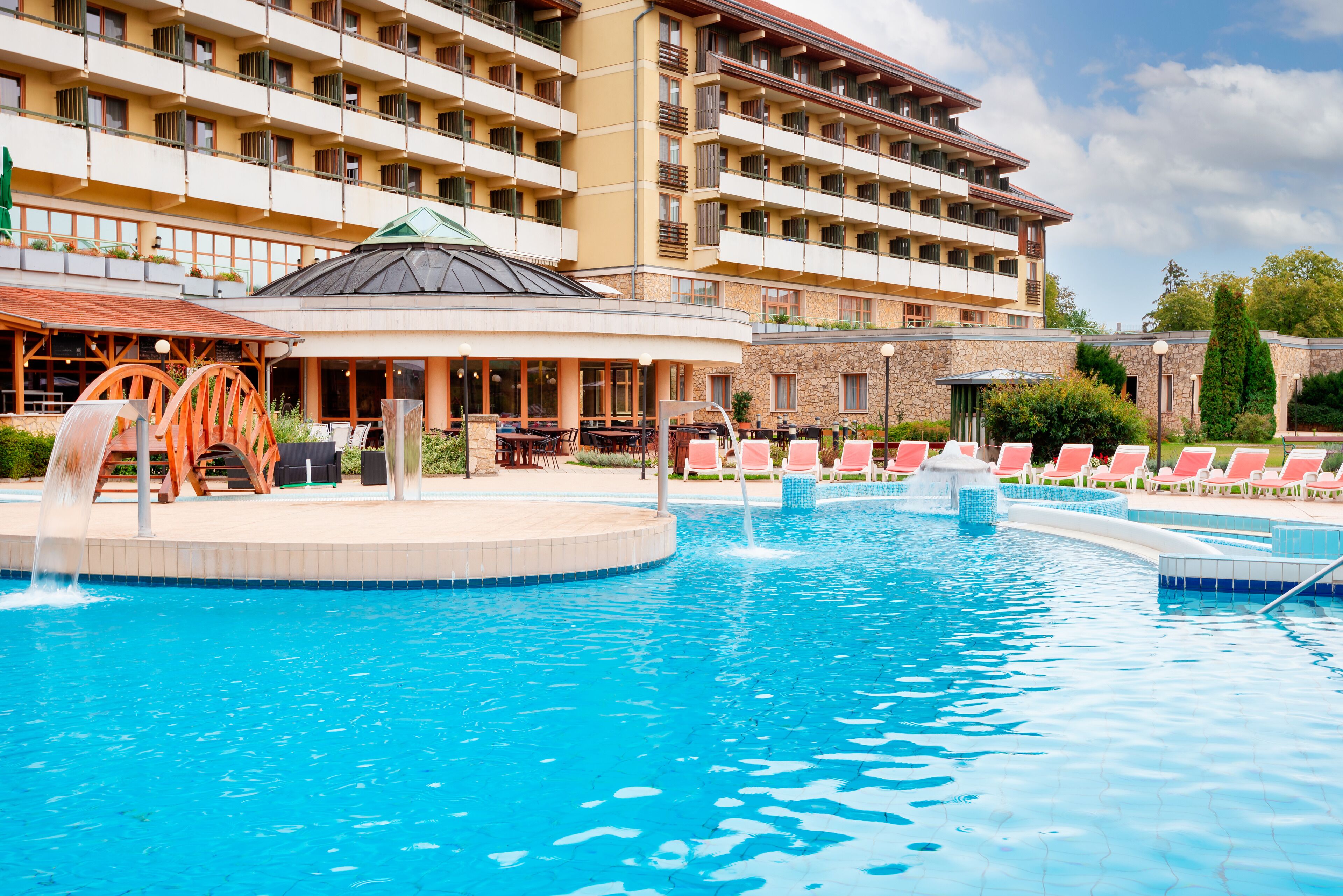 Um hotel com piscina, área de estar ao ar livre e um edifício com vários andares e varandas.