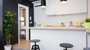 Cozinha moderna com armários brancos, bancada preta e dois banquetes pretos.