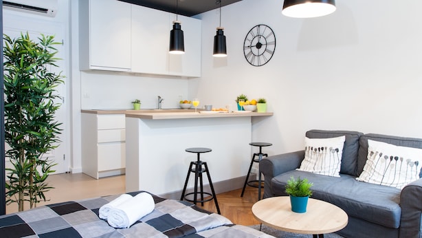 Um espaço habitacional moderno e compacto com cozinha americana, área de refeições e sofá.