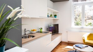 Uma cozinha moderna com pia embutida, TV de tela plana e área de jantar com uma cadeira amarela e uma mesa pequena.