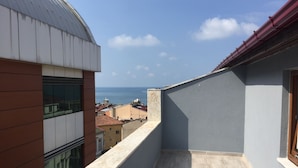Uma varanda com vista para o mar e edifícios vizinhos.