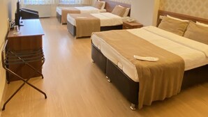 Quarto de hotel com três camas, uma escrivaninha e uma cadeira.