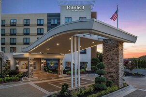 Entrada de um hotel Fairfield by Marriott, com galeria coberta, pilares de pedra e jardim ajardinado.