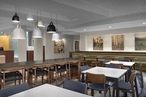 Interior moderno de restaurante com balcão extenso, diversas opções de assento e iluminação pendente.