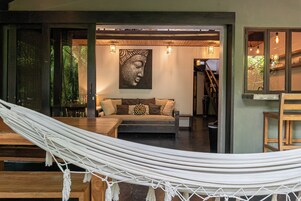 Uma rede em um quarto com sofá, pintura de Buda e escada.