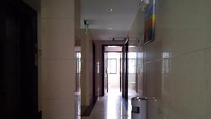Um corredor com paredes azulejadas, uma lixeira e uma porta no final.