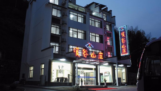 Um hotel com vários andares, um grande letreiro de neon e entrada com tapete vermelho.