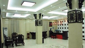 Um saguão com mobiliário tradicional, um balcão de recepção e pilares decorativos.